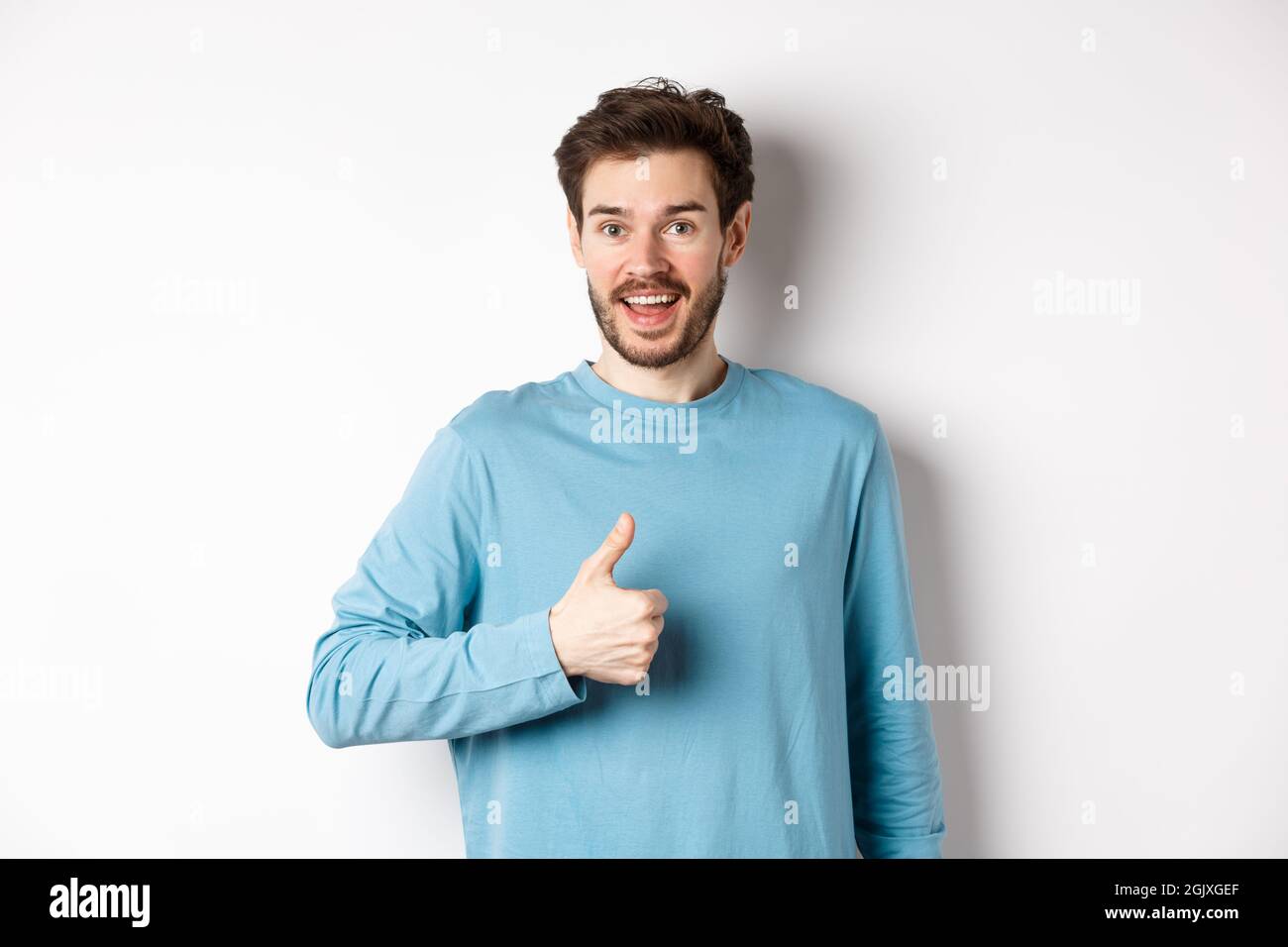 Cheerful young man agree and say yes, show thumb up in approval ...