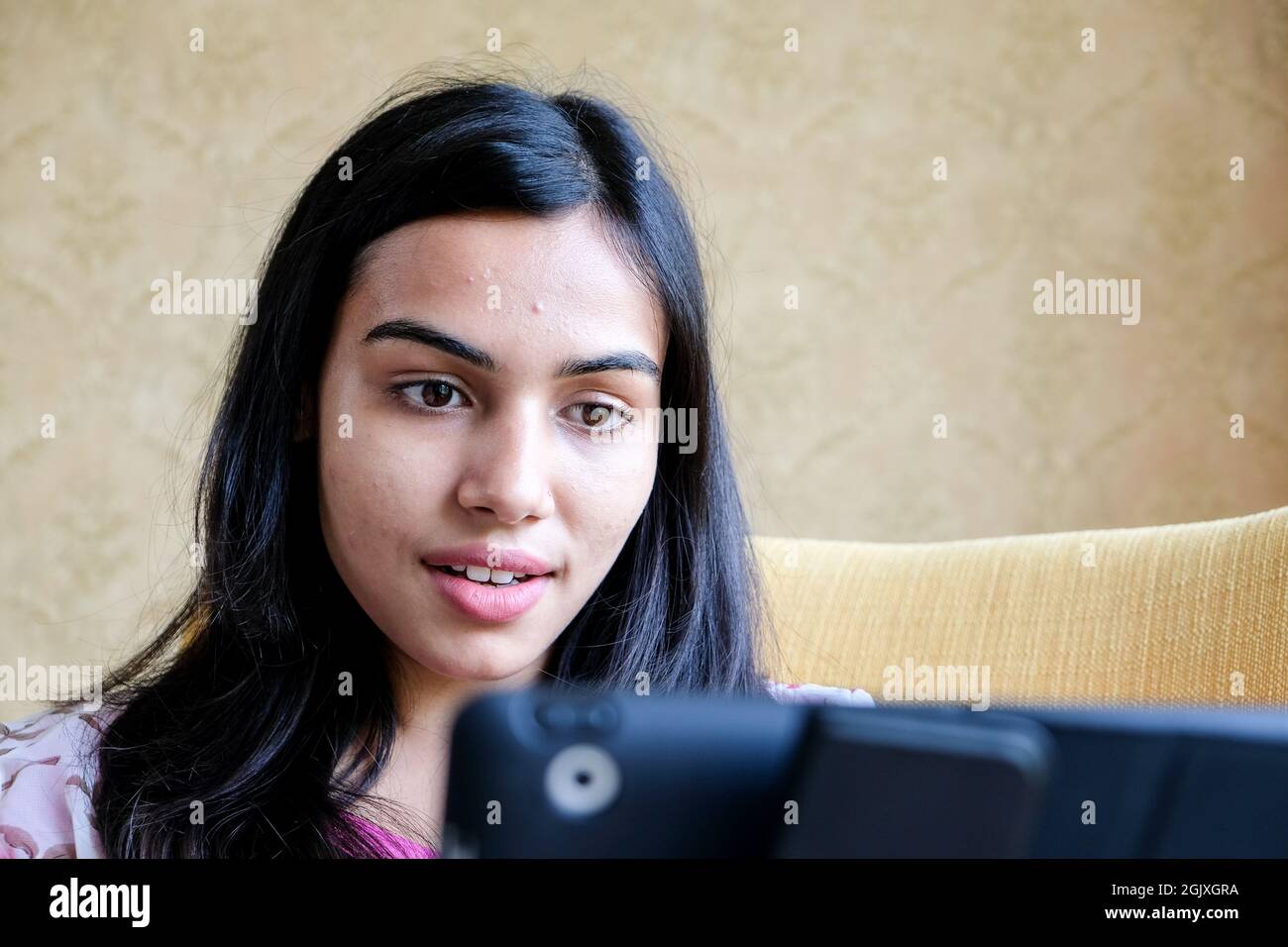 An Indian lady watching a video on a tablet while sitting on the ...