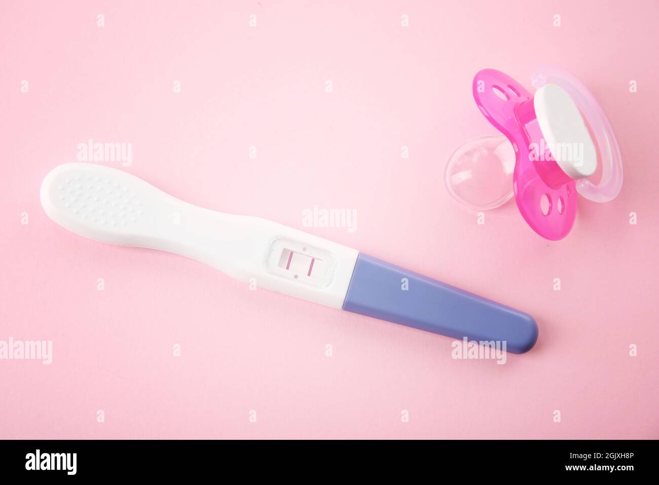 Pregnancy test and pacifier on pink background. Baby born concept Stock ...