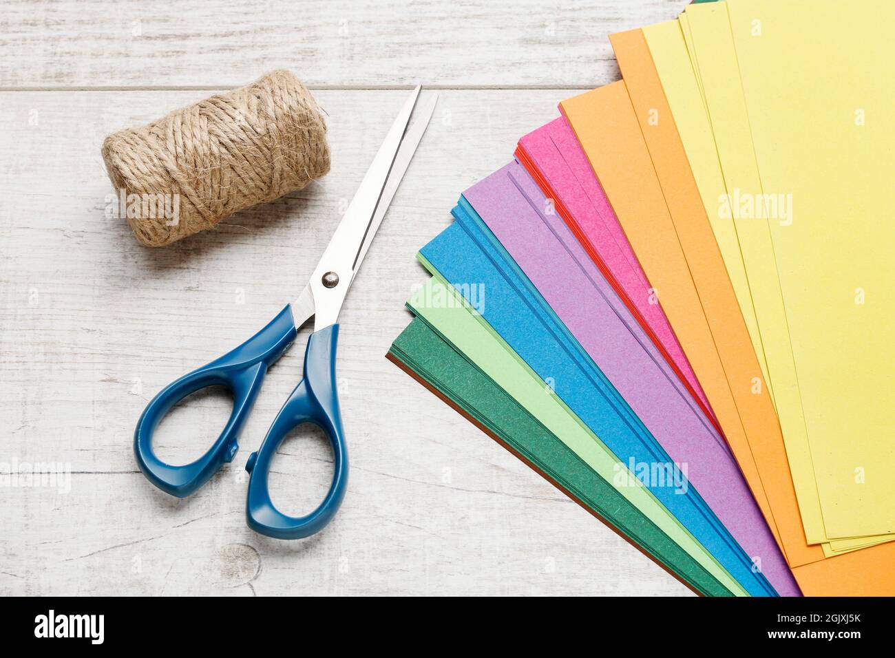 Colorful sheets of paper, scissors and string on wooden table Stock ...