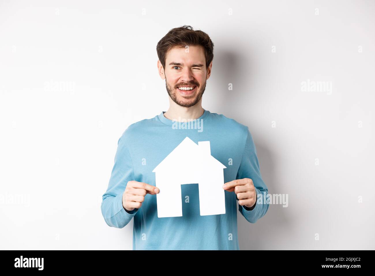 Real estate and insurance concept. Happy young man winking and smiling ...
