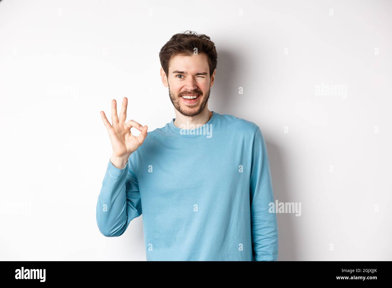 Handsome modern guy feeling confident, showing OK sign and winking at ...