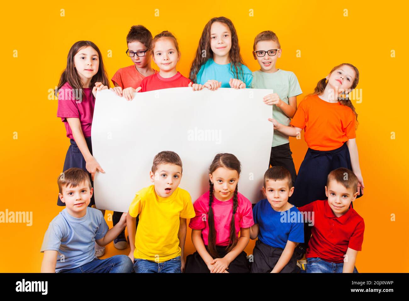The group of kids holding a big white copy space poster Stock Photo - Alamy
