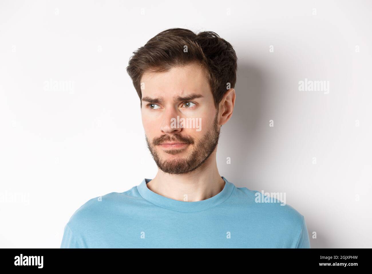 Close-up of disappointed sad man, grimacing and frowning, looking left ...