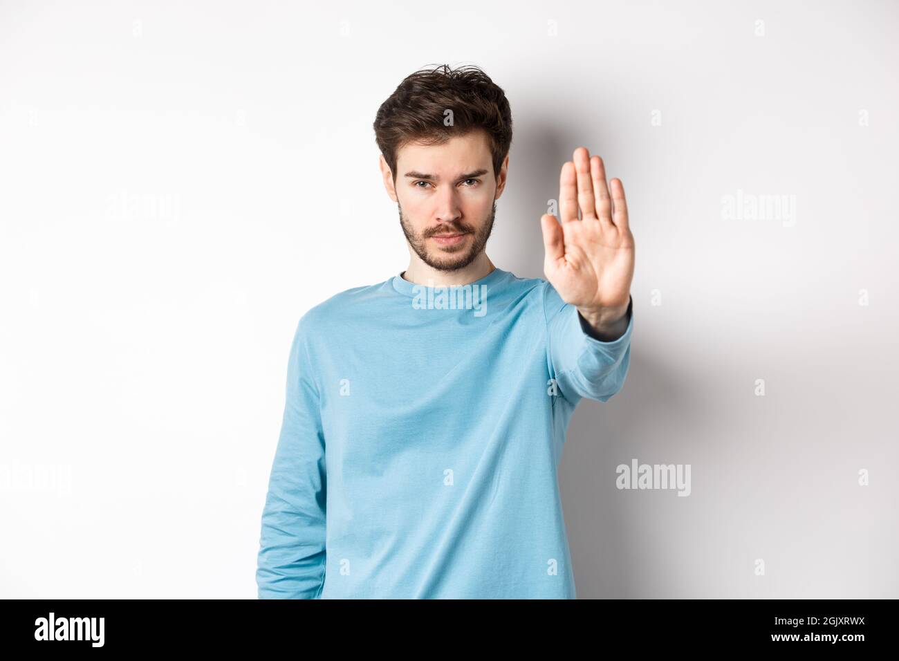 Serious young man looking confident with hand stretched out, saying ...