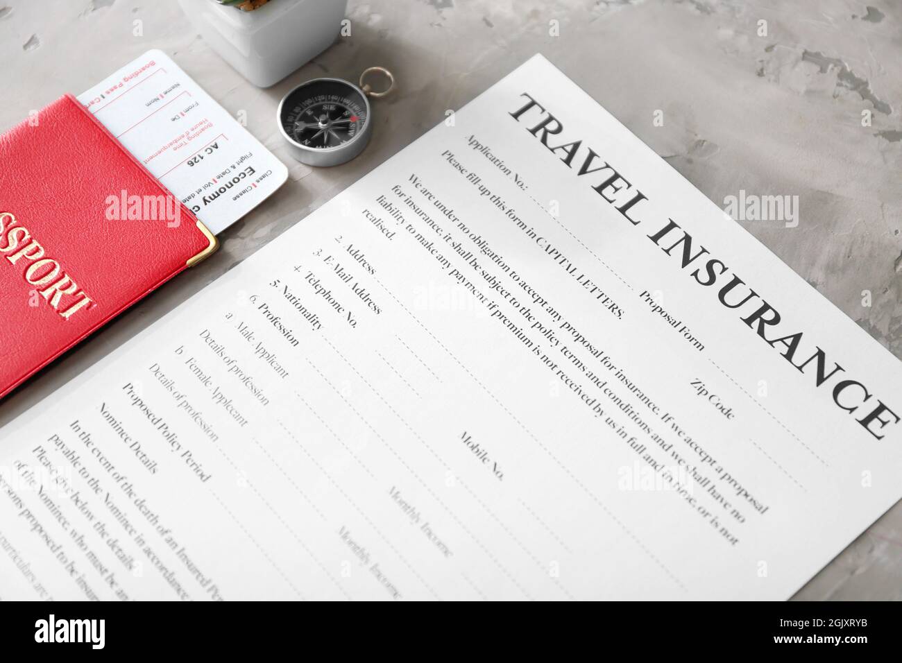 Passport with ticket and blank travel insurance form on grey background ...
