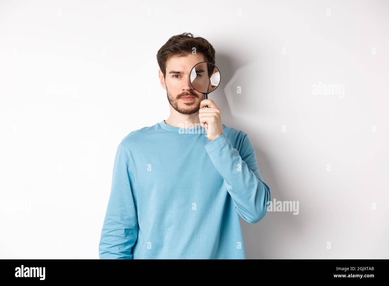 Man searching for something, looking through magnifying glass at camera ...
