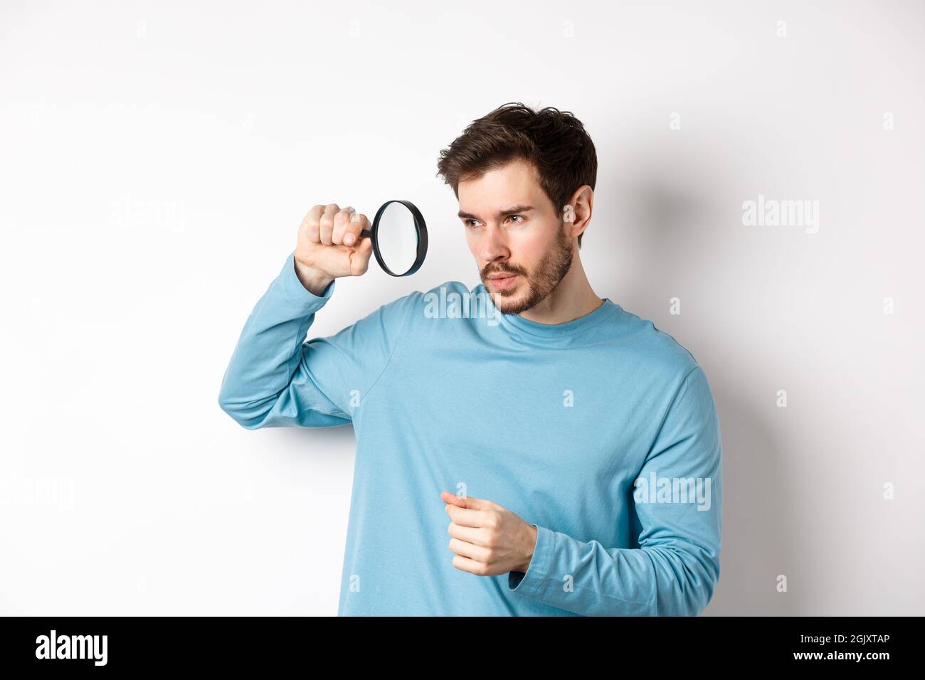 Young handsome man look through magnifying glass with curious face ...