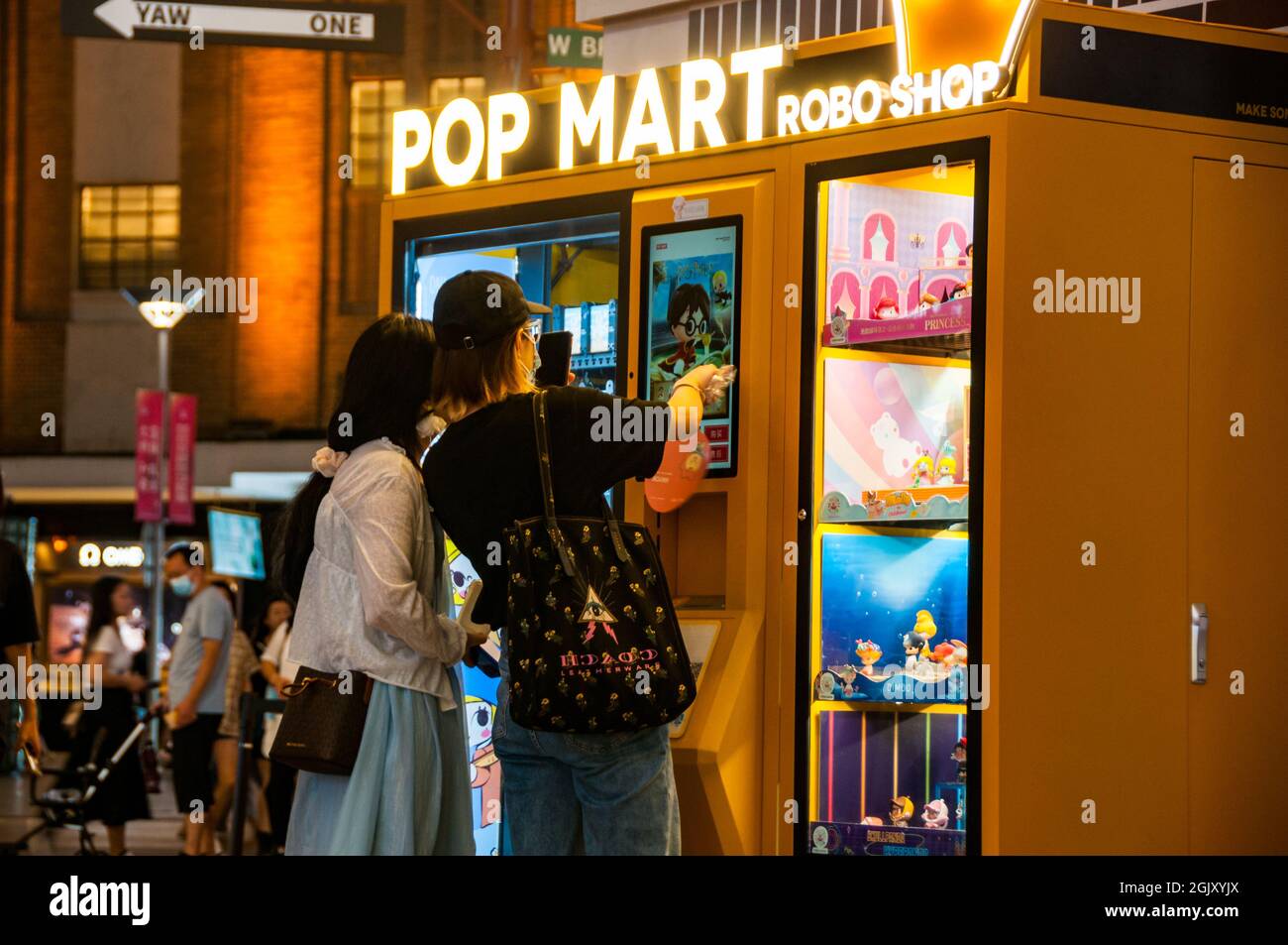 Two young ladies use a Pop Mart Robo Shop machine under the Shimao ...