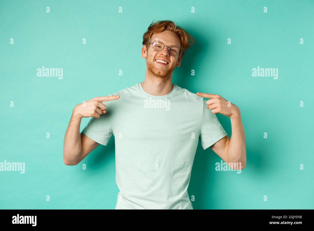 Confident redhead man in glasses and t-shirt, smiling with smug face ...