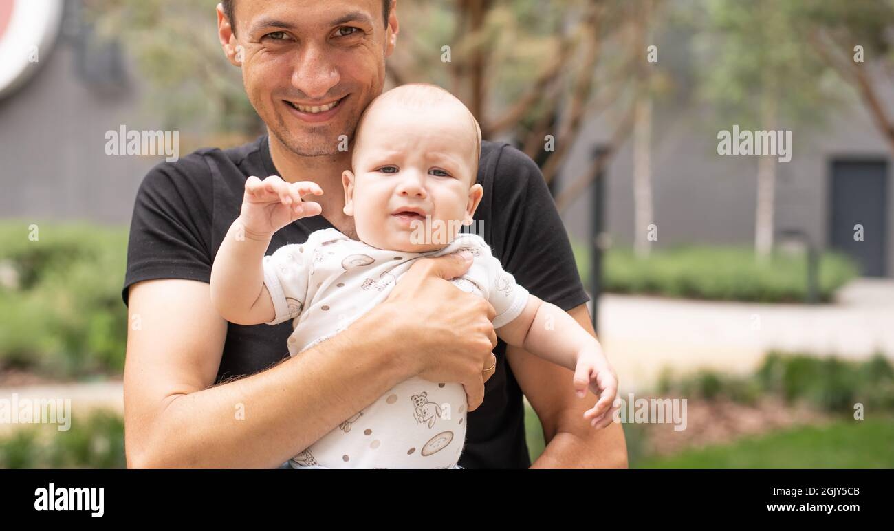 Portrait of young handsome father holding his adorable cute newborn ...