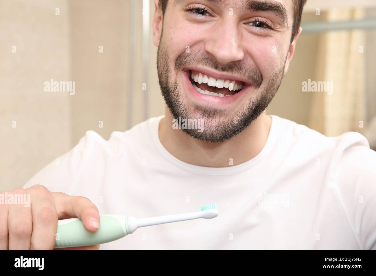 Handsome man brushing teeth in bathroom Stock Photo - Alamy