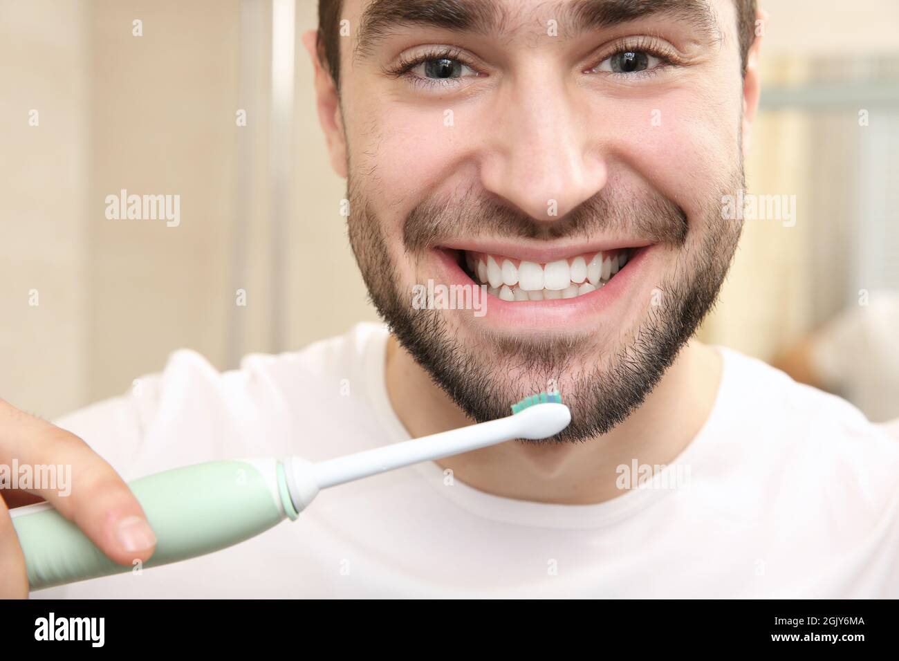 Handsome man brushing teeth in bathroom Stock Photo - Alamy