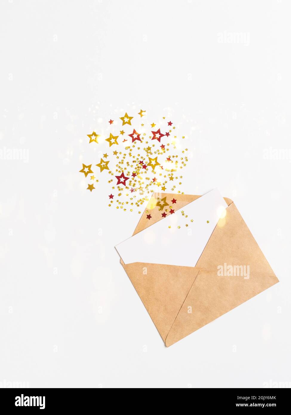 Open brown envelope with blank white card and various stars with ...