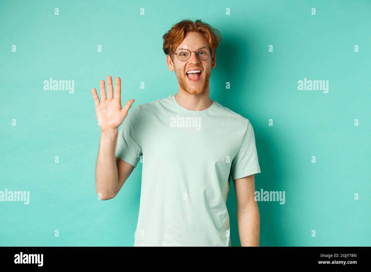 Friendly bearded guy in glasses saying hello, waving hand to greet and ...