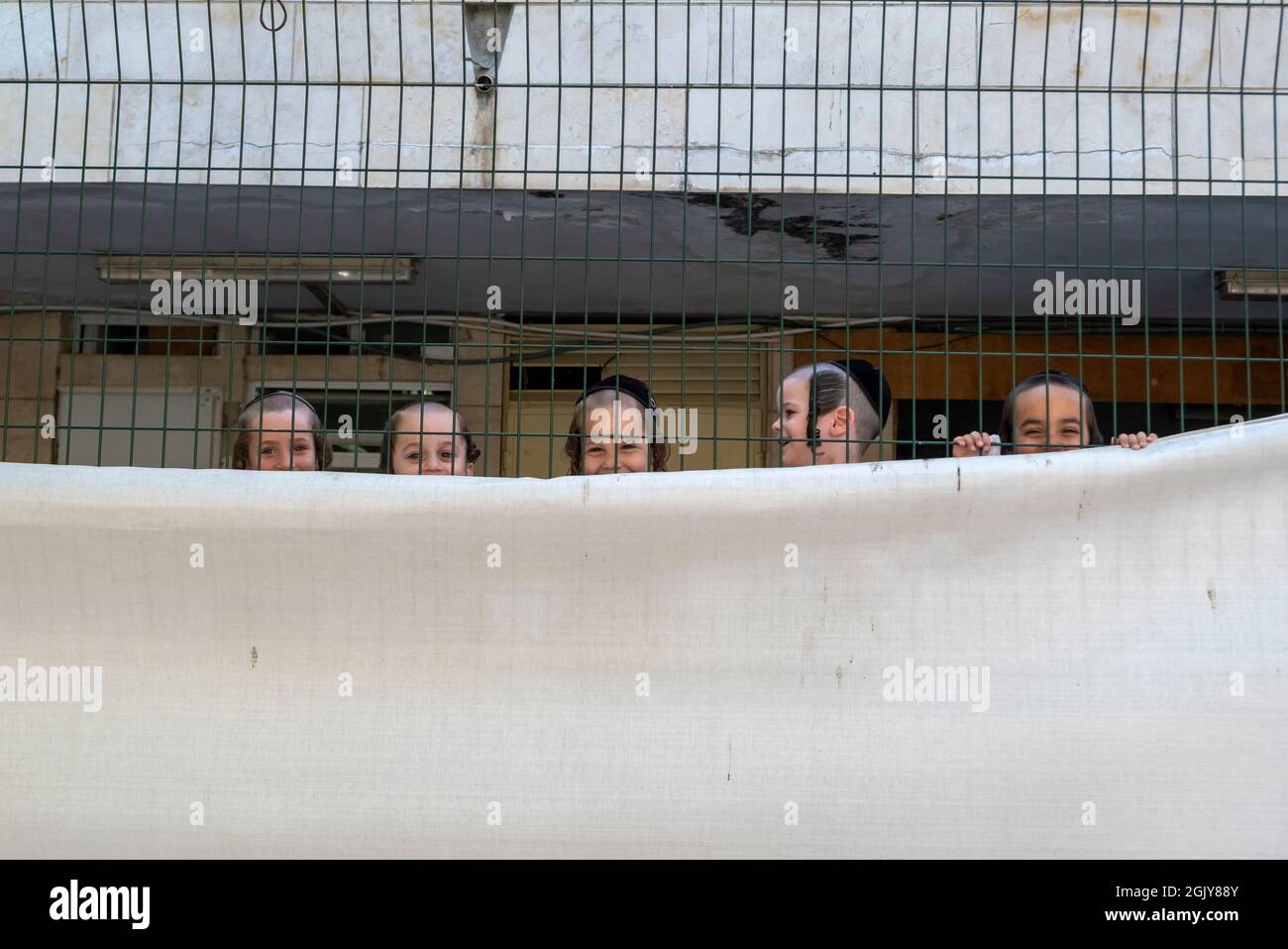 Ultra Orthodox children peer out a fence of a school in the religious ...