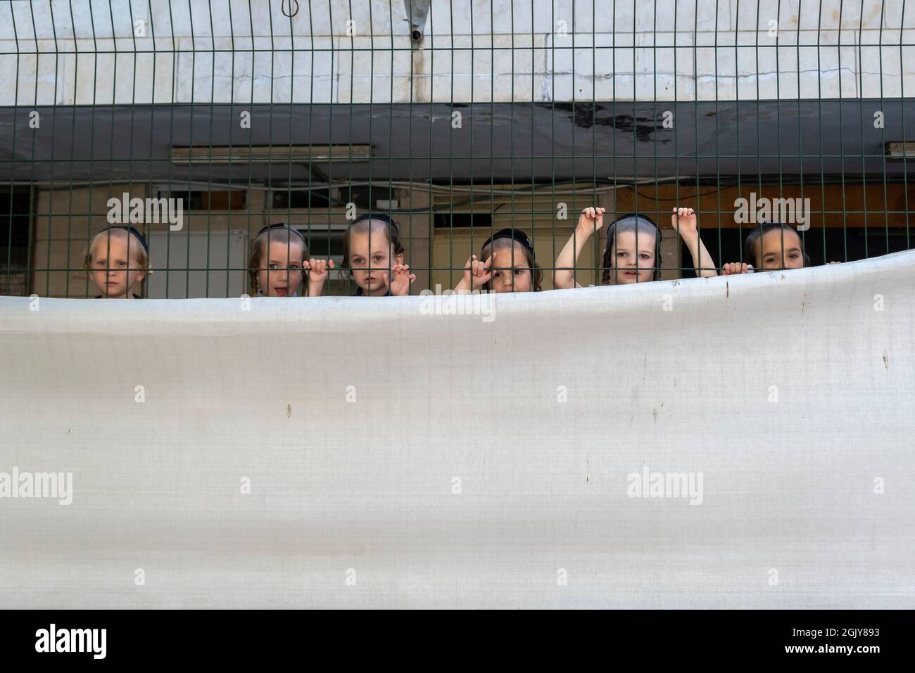 Ultra Orthodox children peer out a fence of a school in the religious ...
