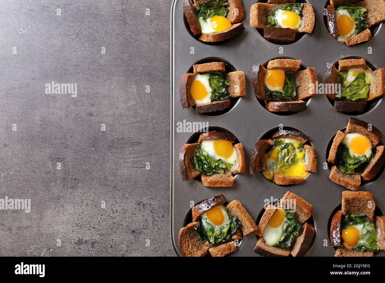 Baking mold with eggs and spinach on gray table Stock Photo - Alamy