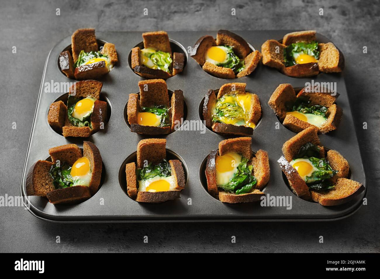 Baking mold with eggs and spinach on gray table Stock Photo - Alamy
