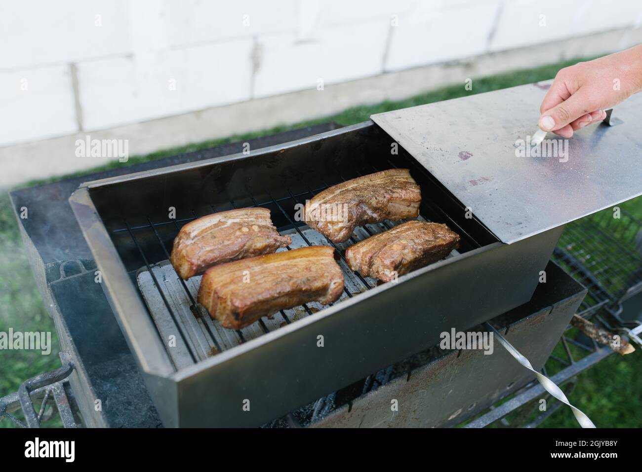 A man's hand opens a smokebox with lard in nature Stock Photo - Alamy
