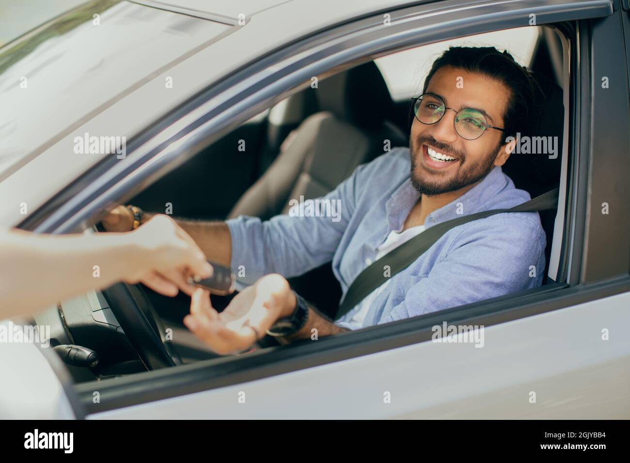 Cheerful arab man taking car key from leasing service employee Stock ...