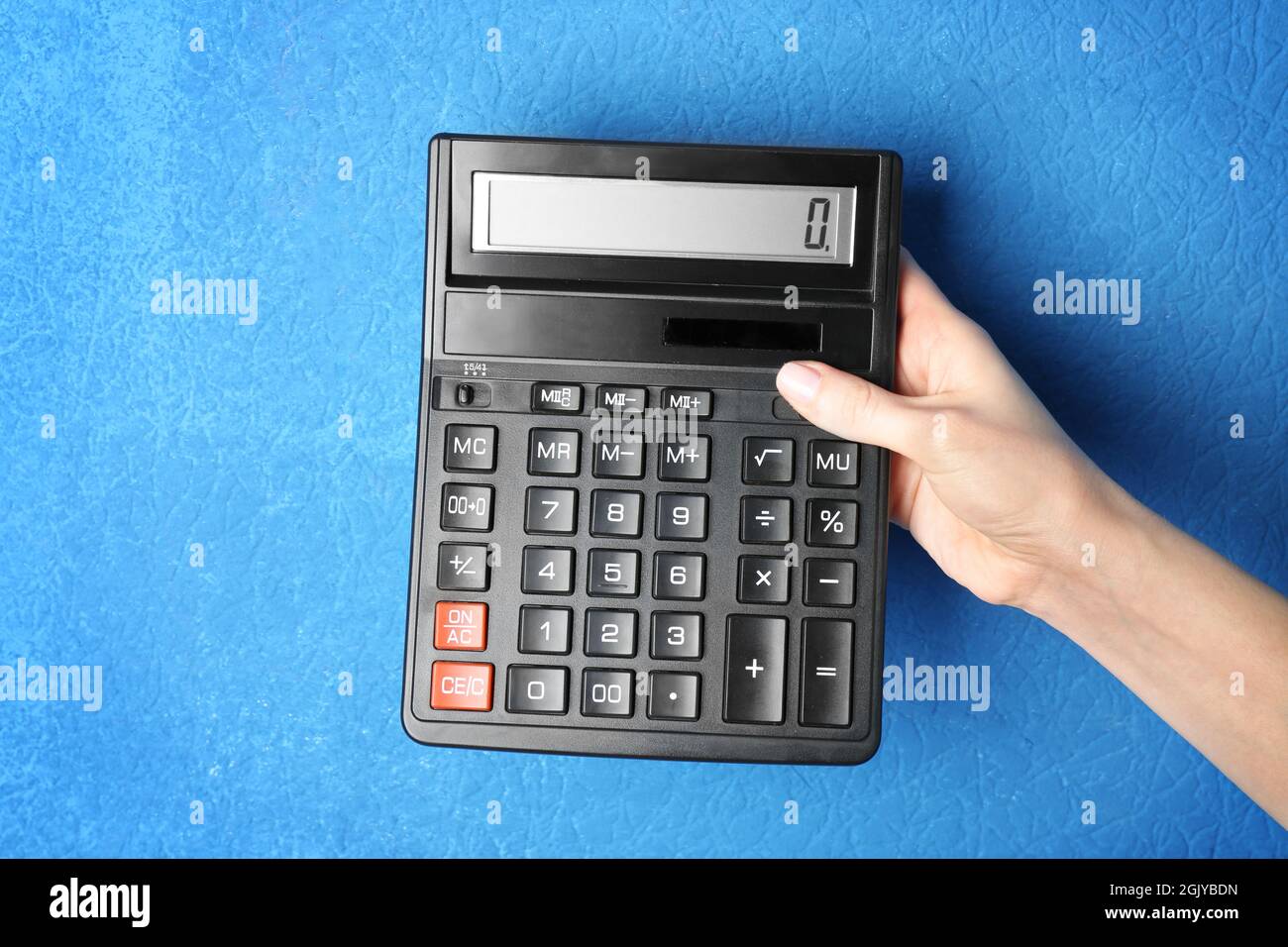 Female hand holding calculator on color background Stock Photo - Alamy
