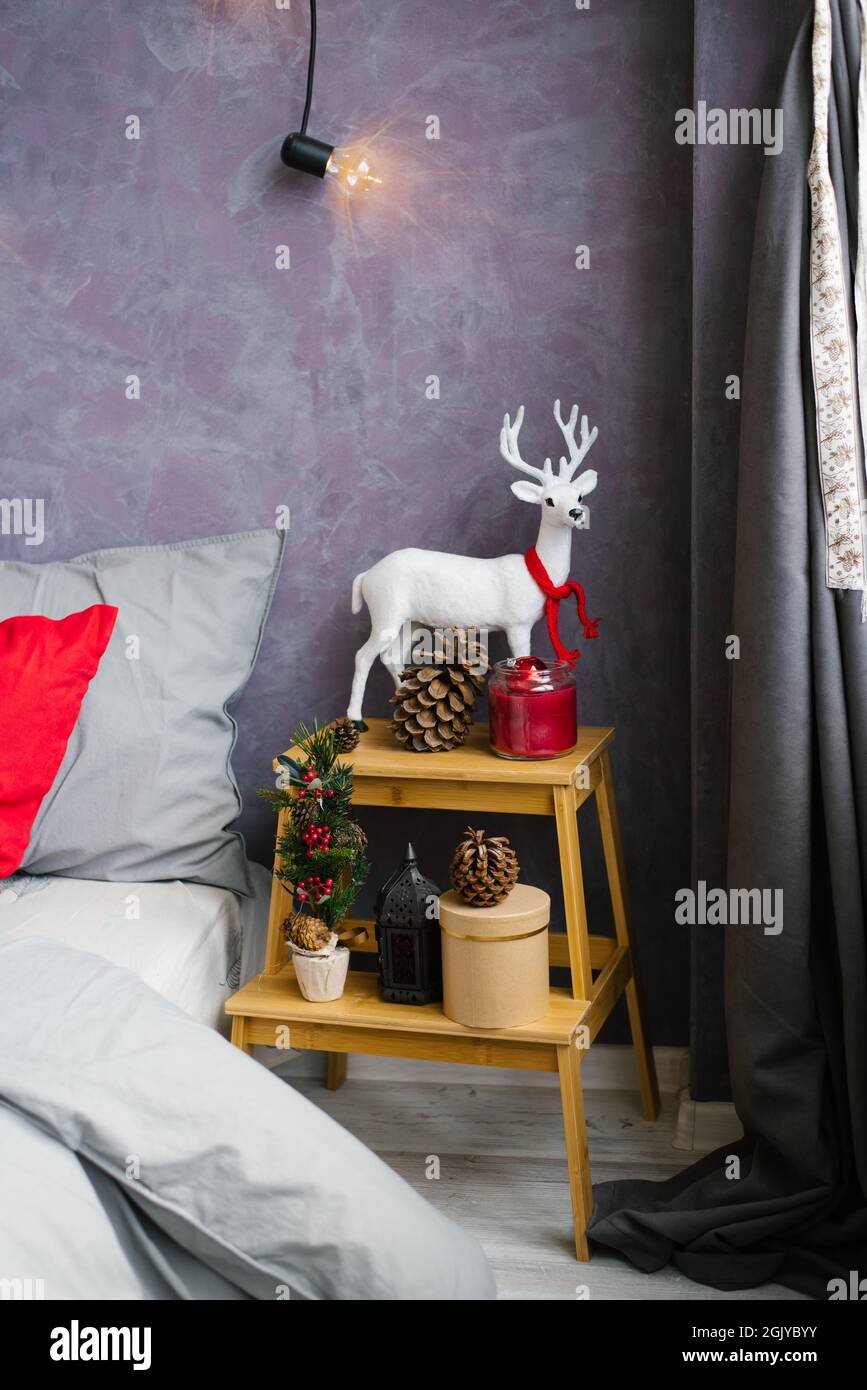 Christmas decor in the bedroom. White deer with red scarf and cones ...