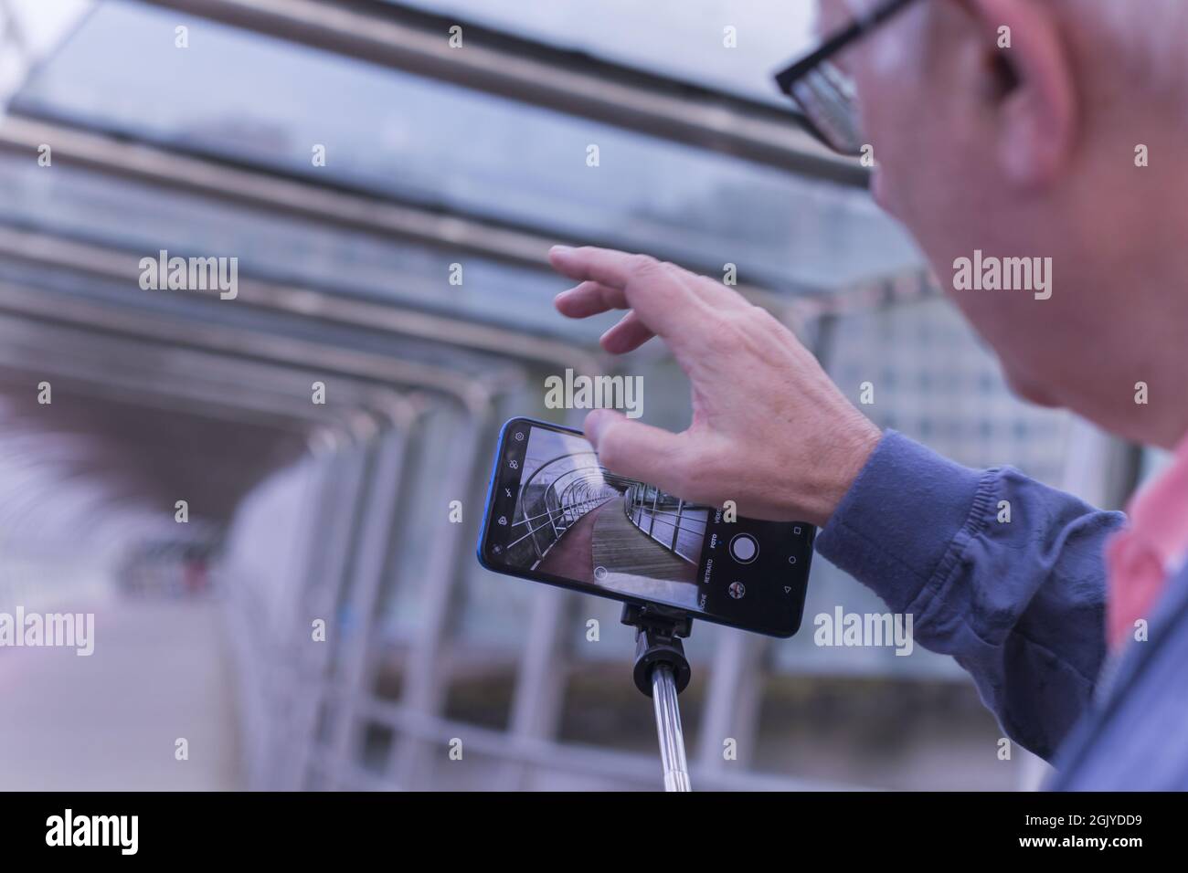 A closeup of an adult man taking a picture of a bridge with a ...
