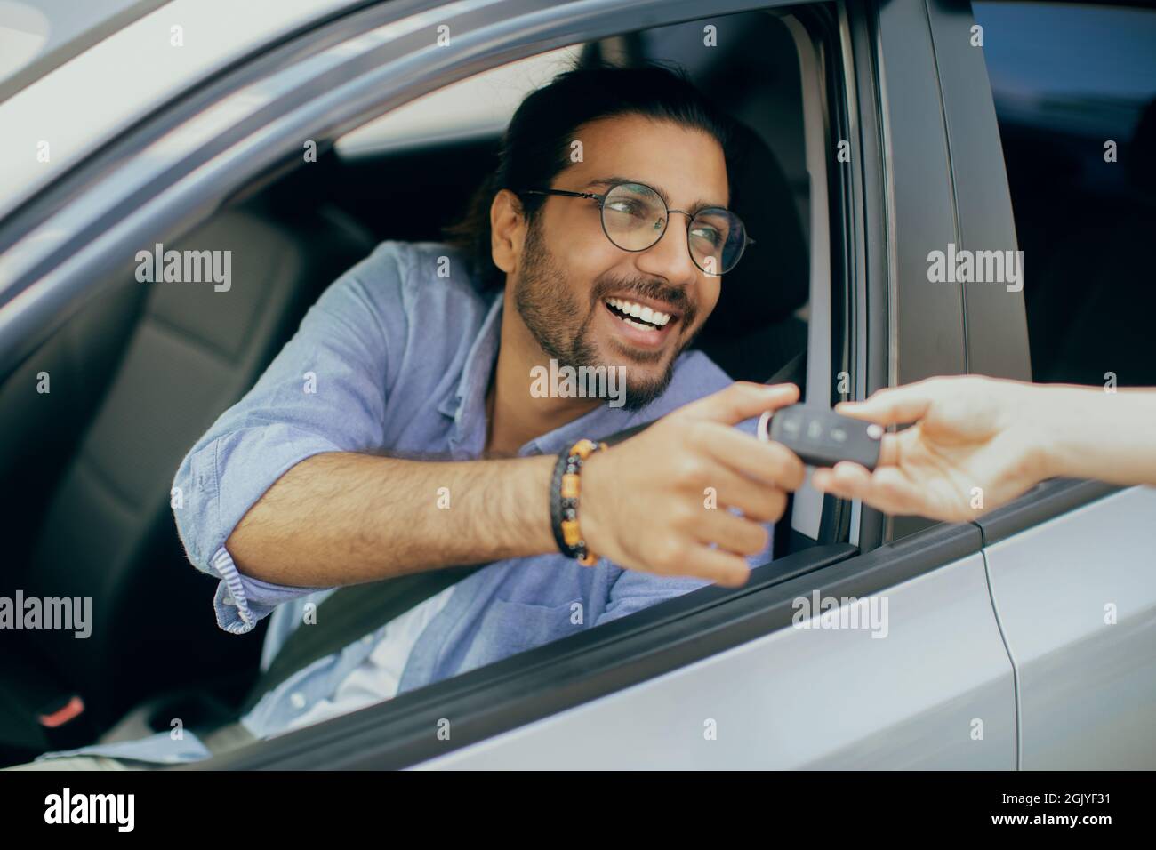 Handsome middle-eastern man taking car key from leasing service person ...