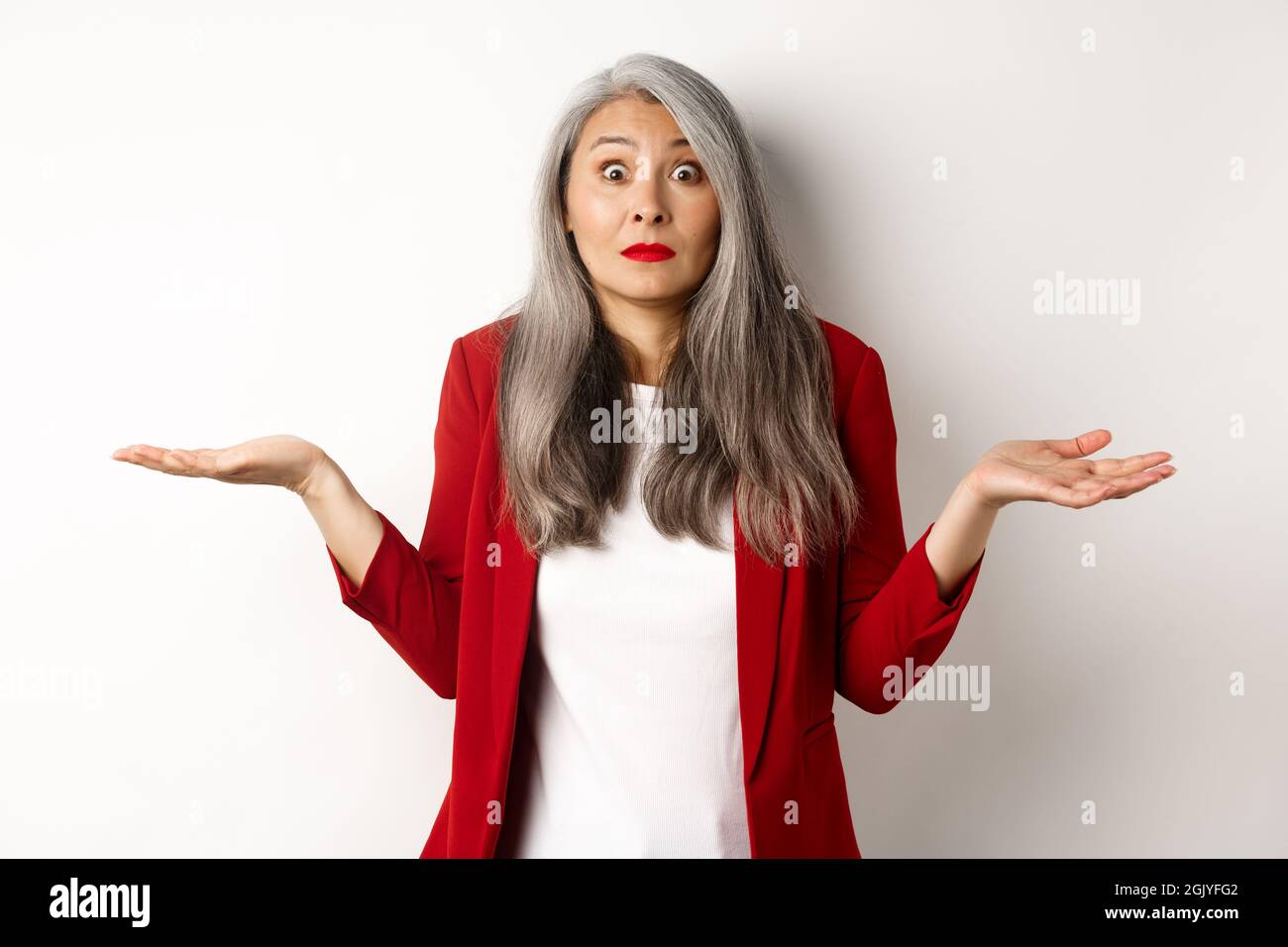 Confused asian senior woman shrugging, spread hands sideways and ...