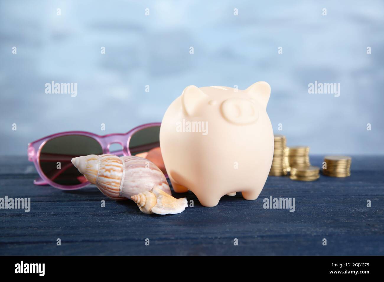 Cute piggy bank with shell, coins and sunglasses on blue background ...