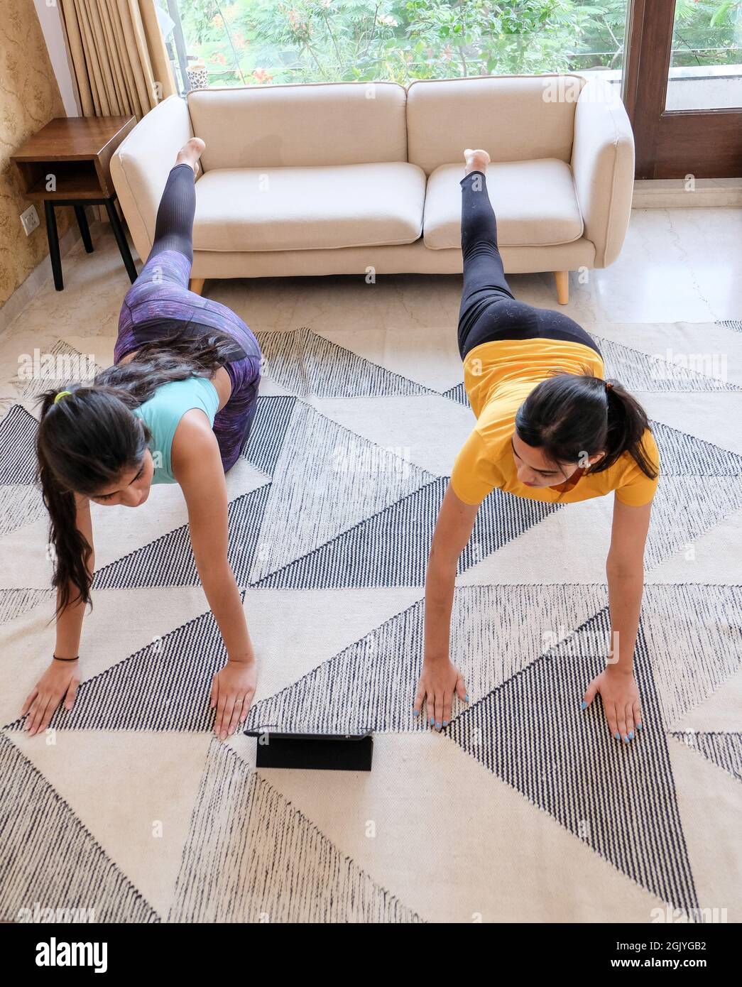 Two pretty Indian friends doing stretching at home Stock Photo - Alamy