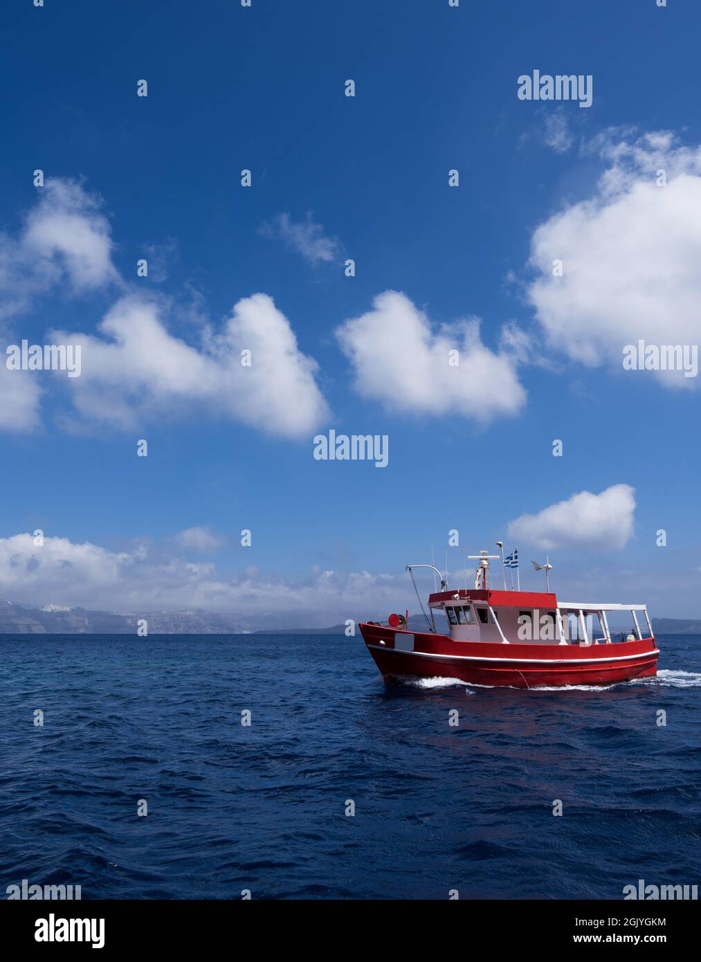 Small red fishing boat in blue sea water. Silhouettes of islands on ...