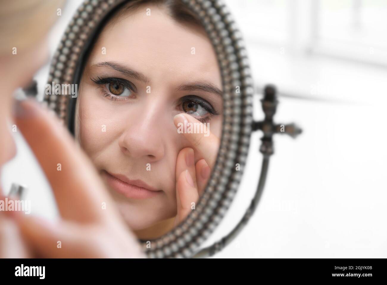 Woman putting contact lenses in front of mirror at home Stock Photo - Alamy