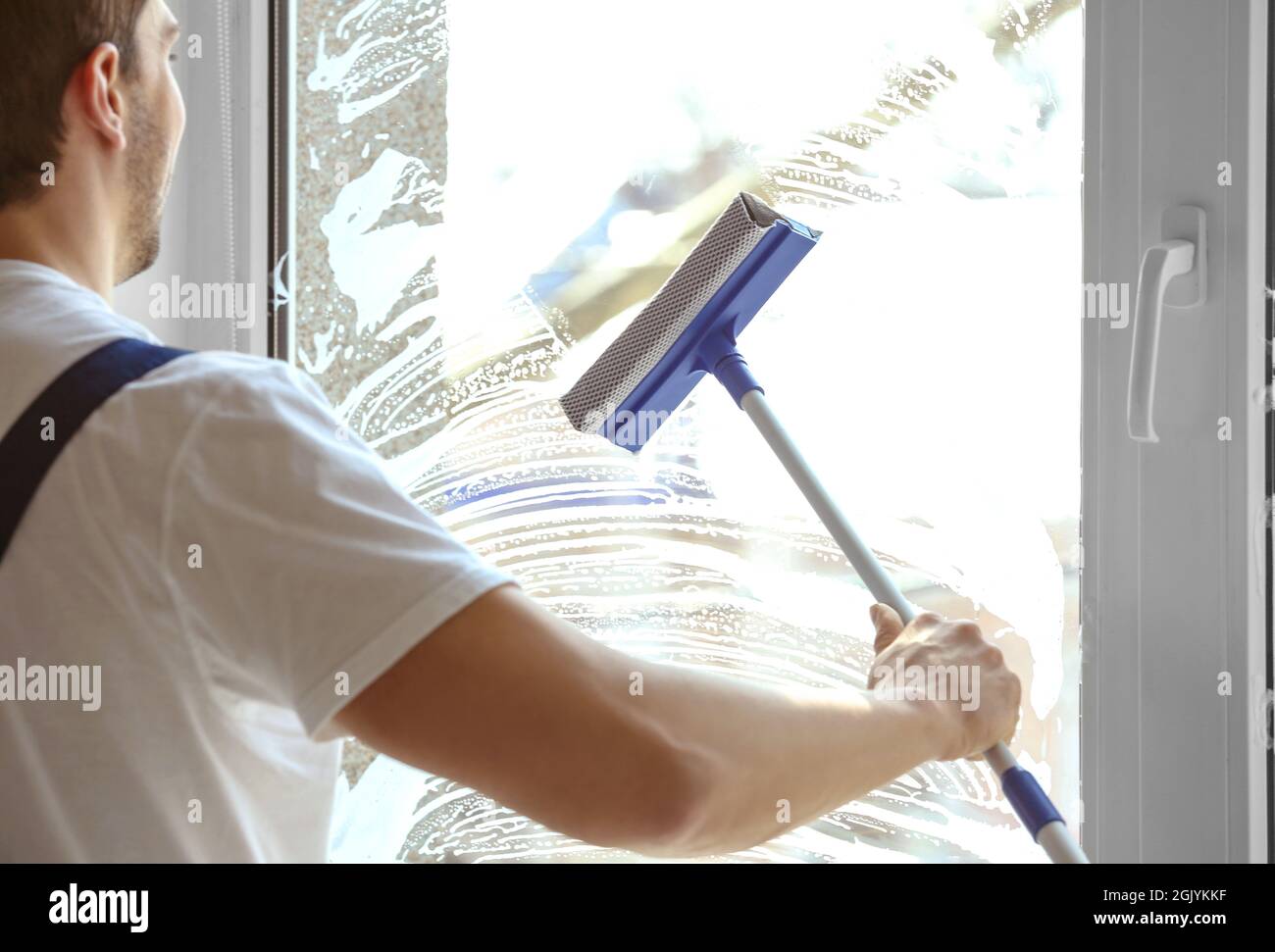 Young man washing window in office Stock Photo - Alamy