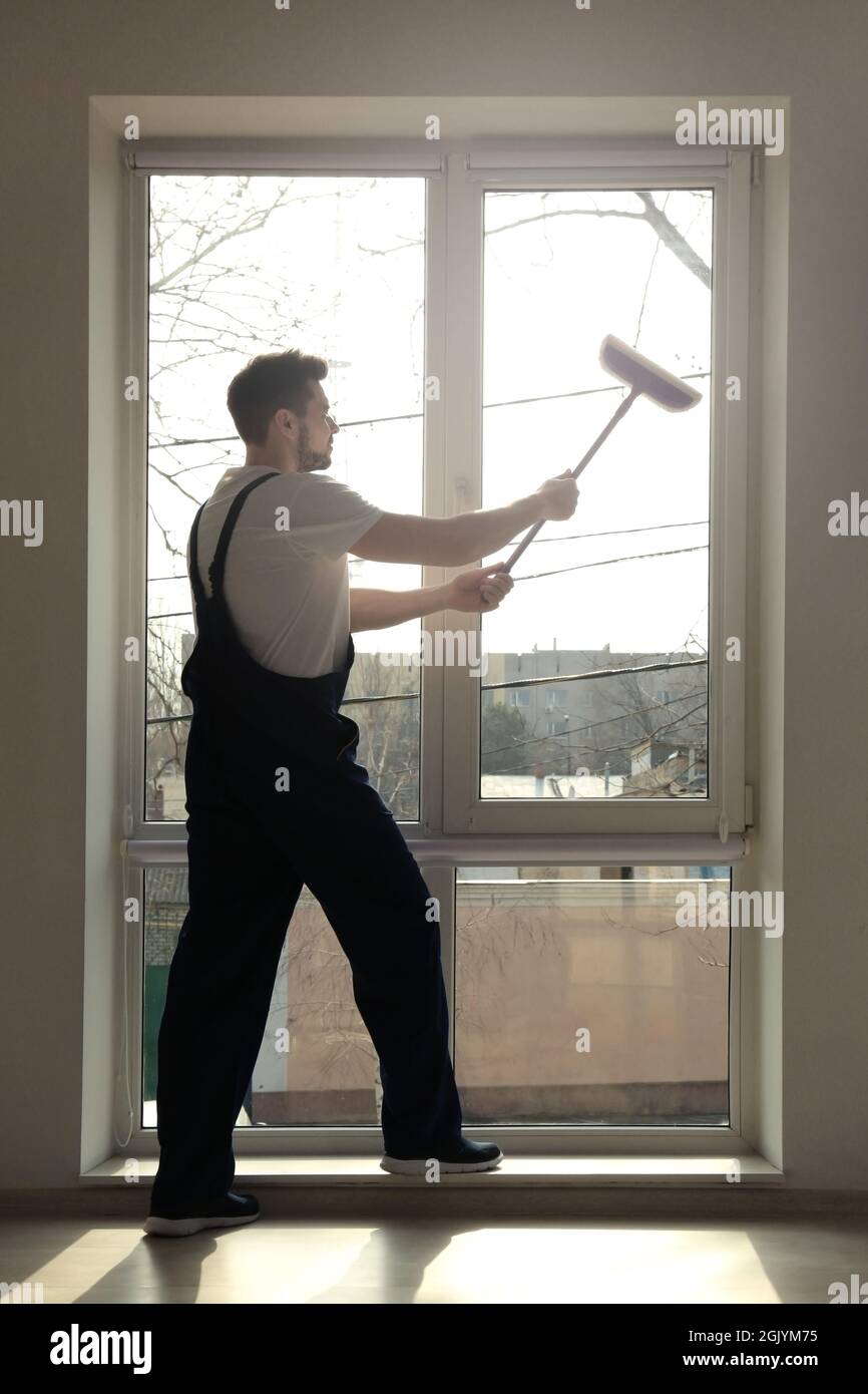 Young man washing window in office Stock Photo - Alamy