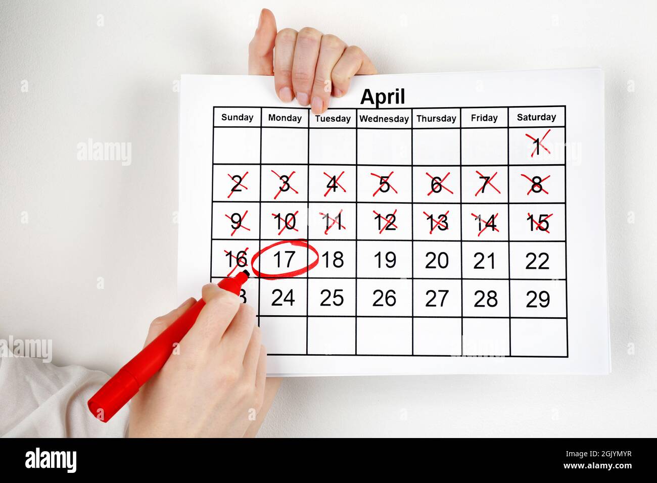 Woman marking date in calendar on white wall background Stock Photo - Alamy