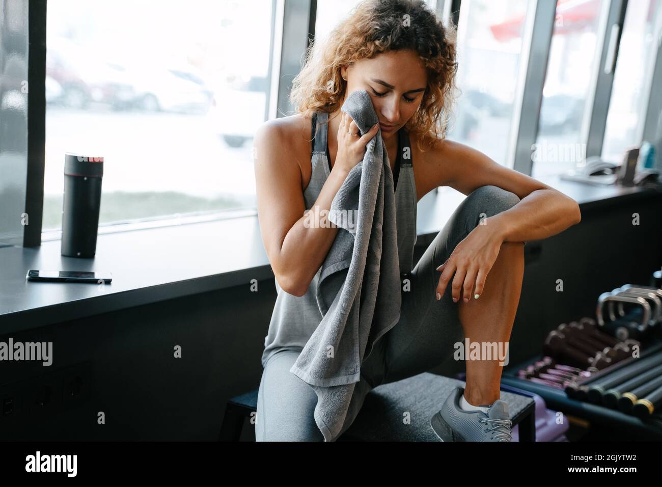 Female athlete after a body workout rests wiping sweat with a towel in ...