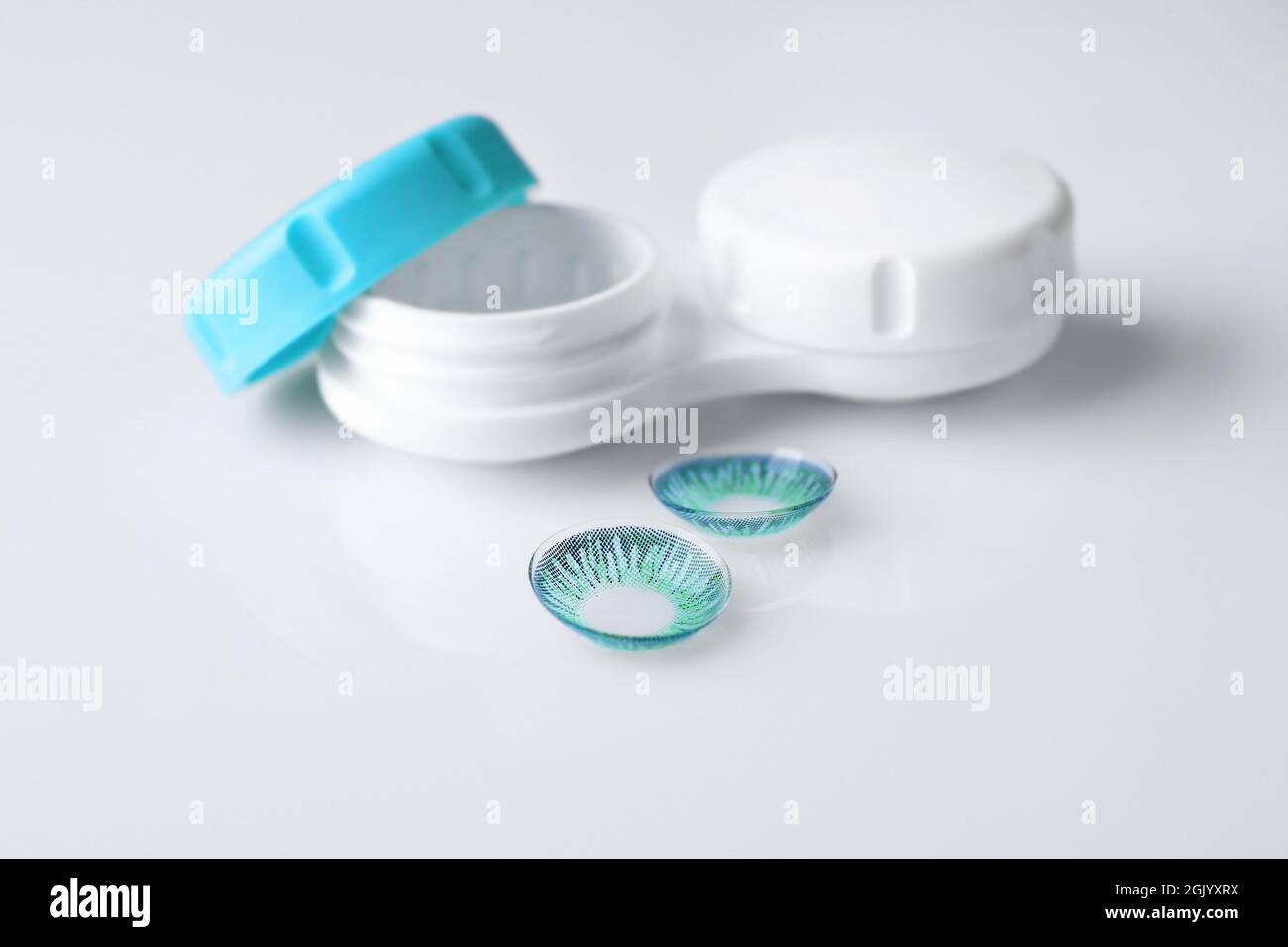 Container with green contact lenses on white background Stock Photo - Alamy