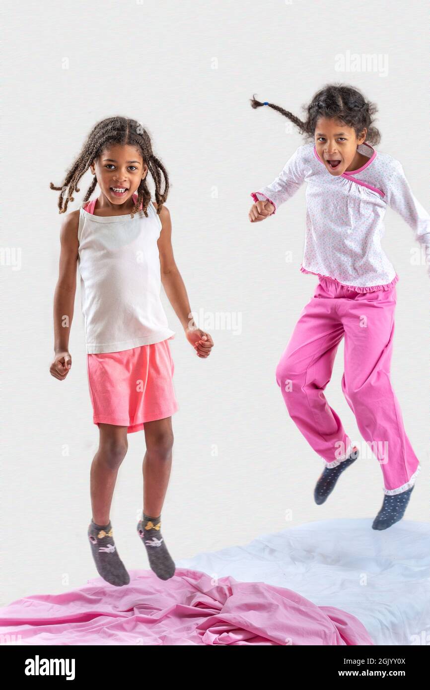 Two little girls jumping in the bed Stock Photo - Alamy