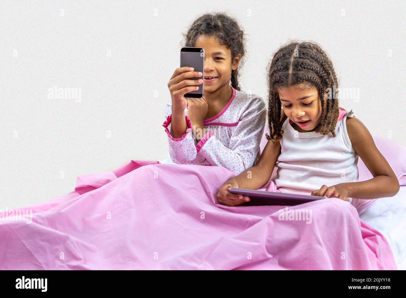 Little girls using digital tablet and smartphone playing in bed Stock ...
