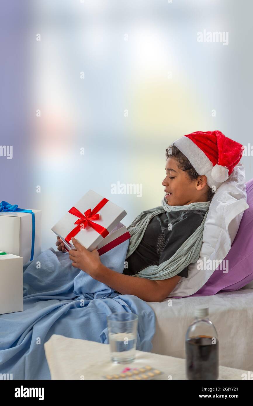 Little boy wearing Santa hat receiving his gift while he is in hospital ...