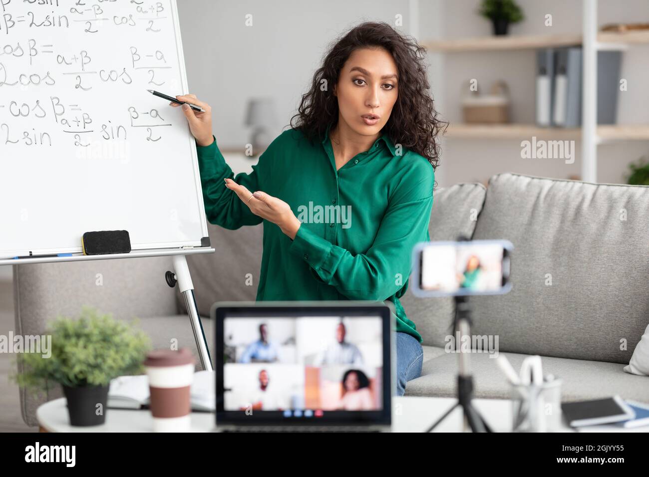Female teacher explaining math online showing clipboard to laptop Stock ...