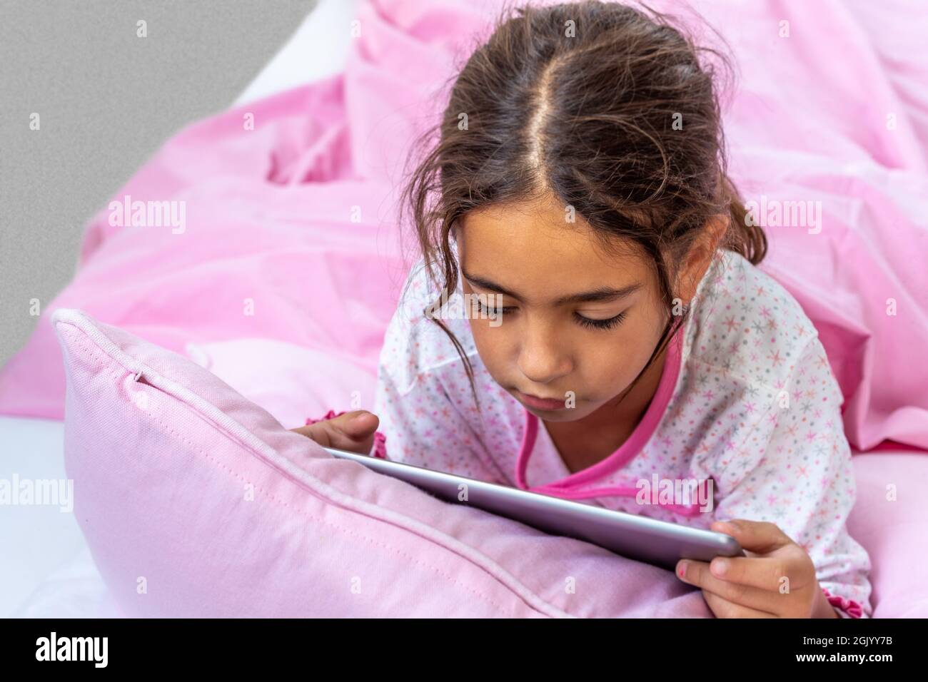 Little girl using digital tablet and playing in bed Stock Photo - Alamy