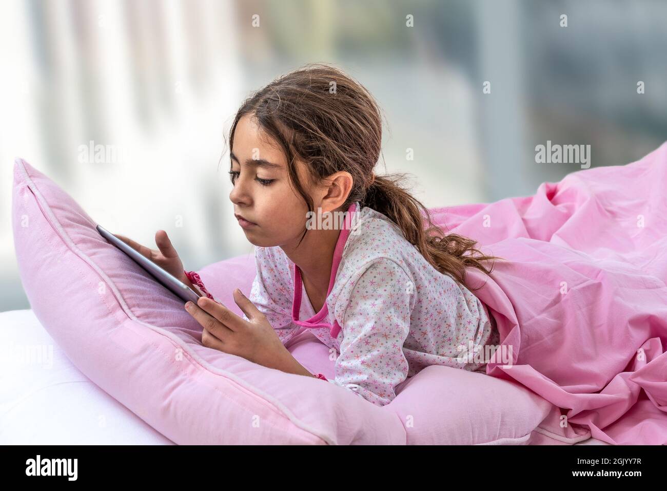 Little girl using digital tablet and playing in bed Stock Photo - Alamy
