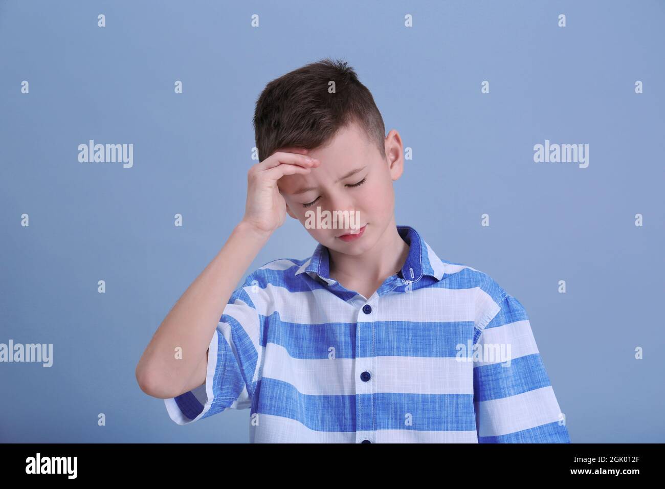Cute boy suffering from headache on color background Stock Photo - Alamy