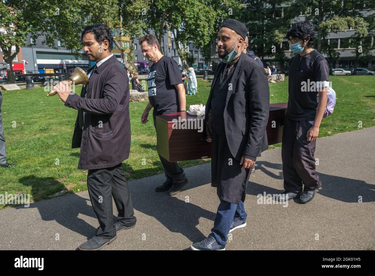 London, UK. 12th Sep 2021. A man rings a bell as a coffin is brought to ...