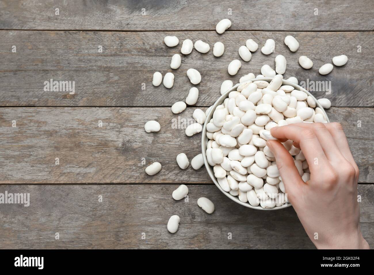 Female hand taking butter bean from bowl on wooden background Stock ...