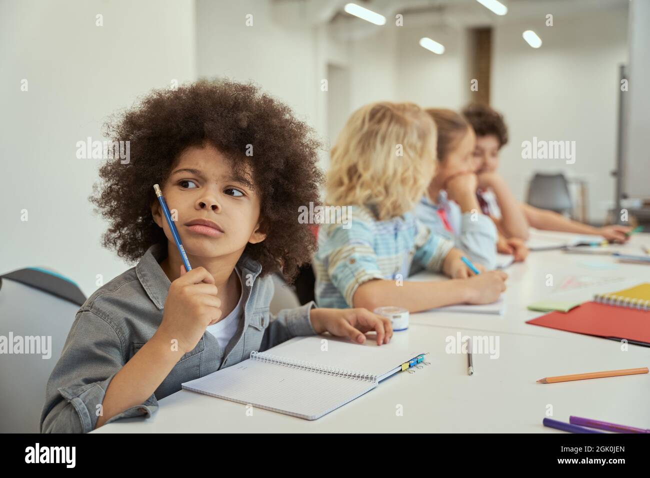 Curious little boy looking away during lesson. Kids studying and making ...