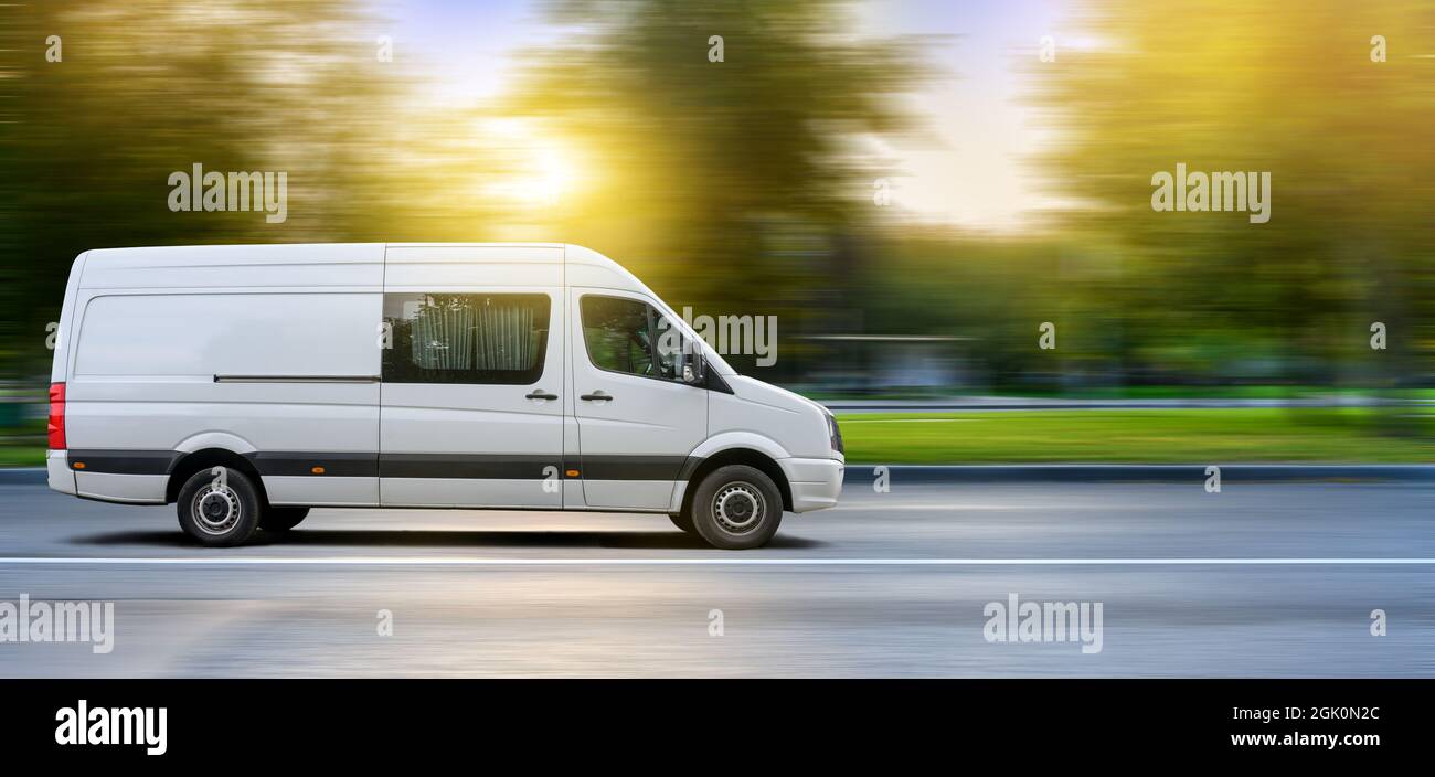 White van moving on a city road at sunset landscape background Stock ...